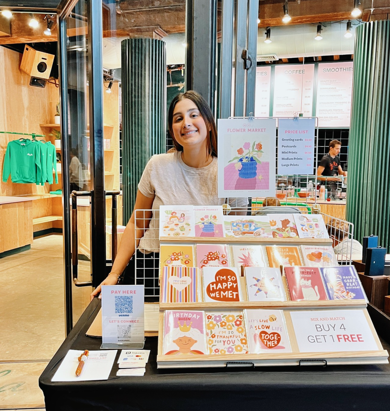 Andrea Pardo standing behind her handmade cards and artwork